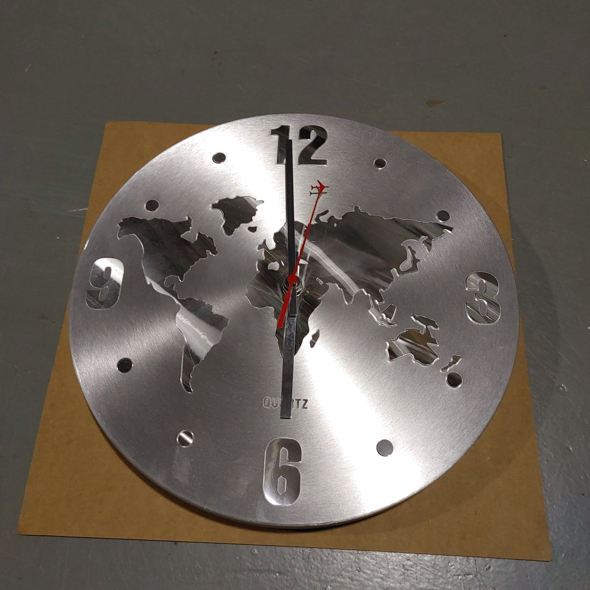 Wall clock metal world with continents and red airplane on hand ...